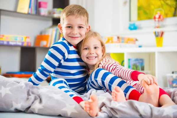 Two happy siblings in sleepwears in bed - Stock Image - Everypixel