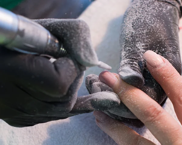 The master uses an electric machine to remove the nail polish on the ...