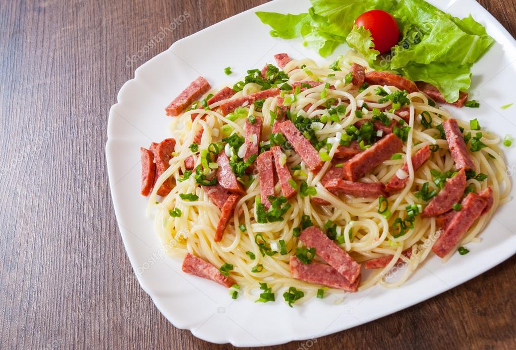 Spaghetti pasta with salami sausage in a plate on wooden table — Stock ...