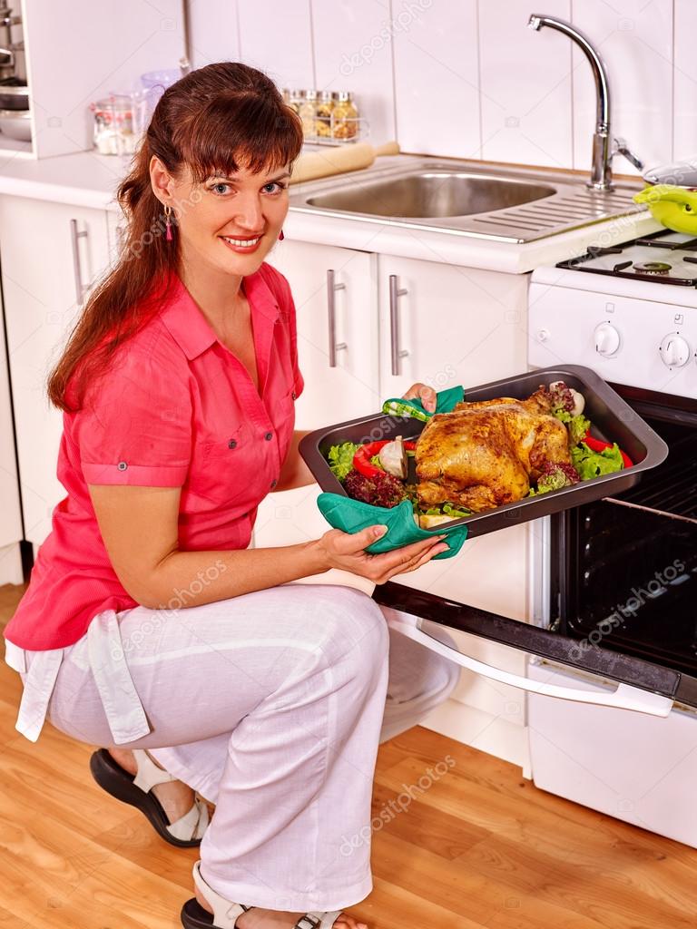Woman cooking chicken at kitchen. Stock Photo by ©poznyakov 104524796