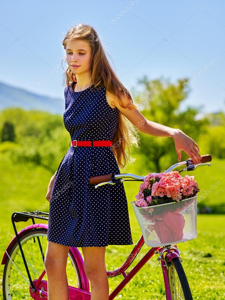 Girl Wearing Blue Sundress Rides Bicycle With Flowers Basket Stock
