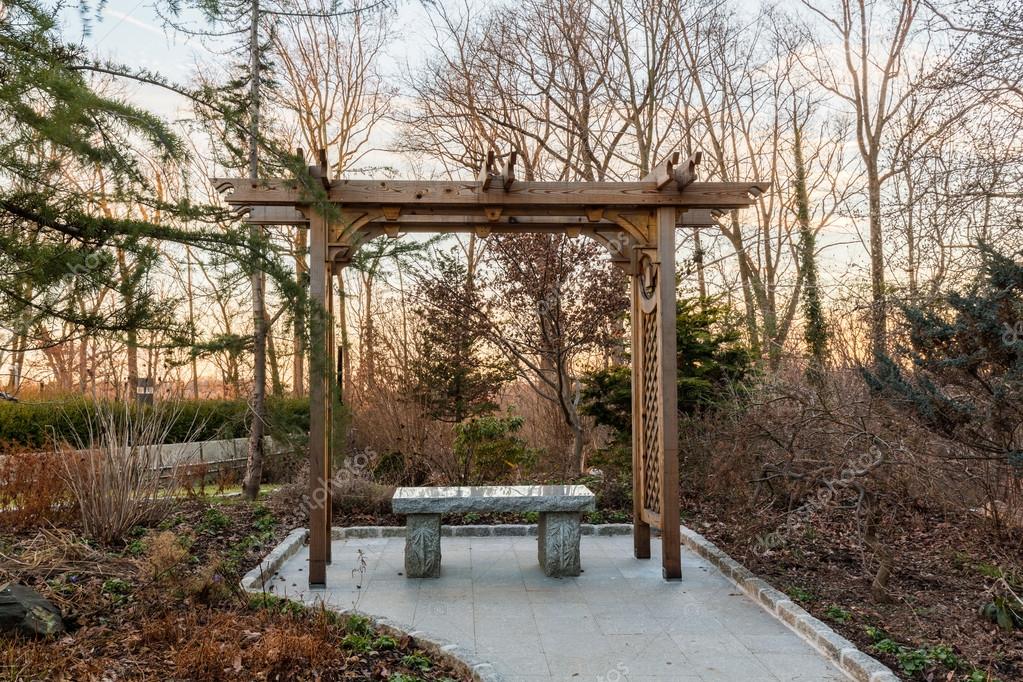 Wooden arbor in forest with stone seat — Stock Photo © steveheap #61662509