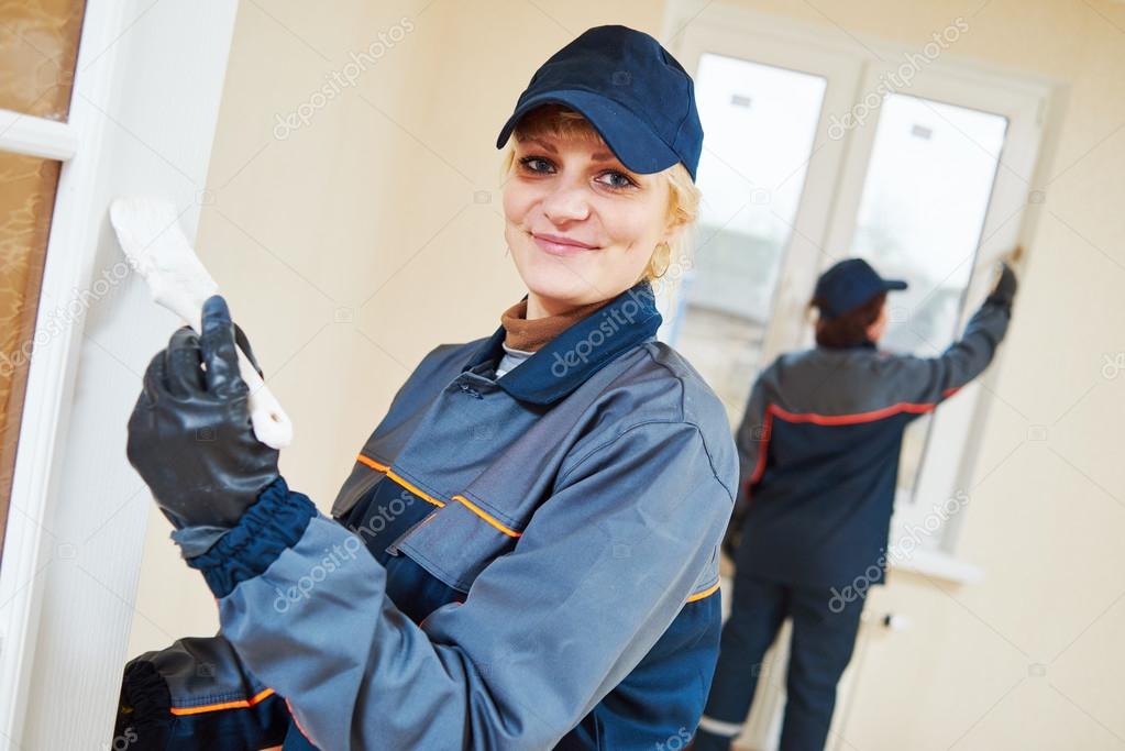 Painting works. Female smiling painter with paint brush at renovation ...