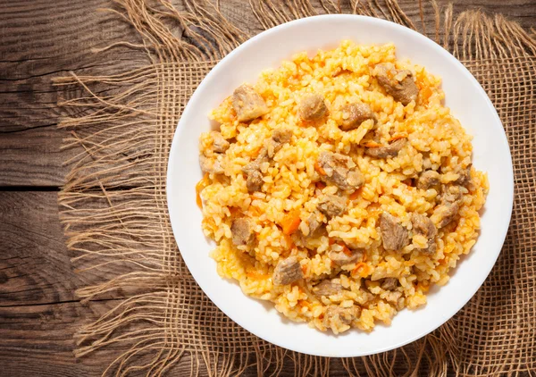 Un delicioso pilaf en un plato en el tablero viejo 2023