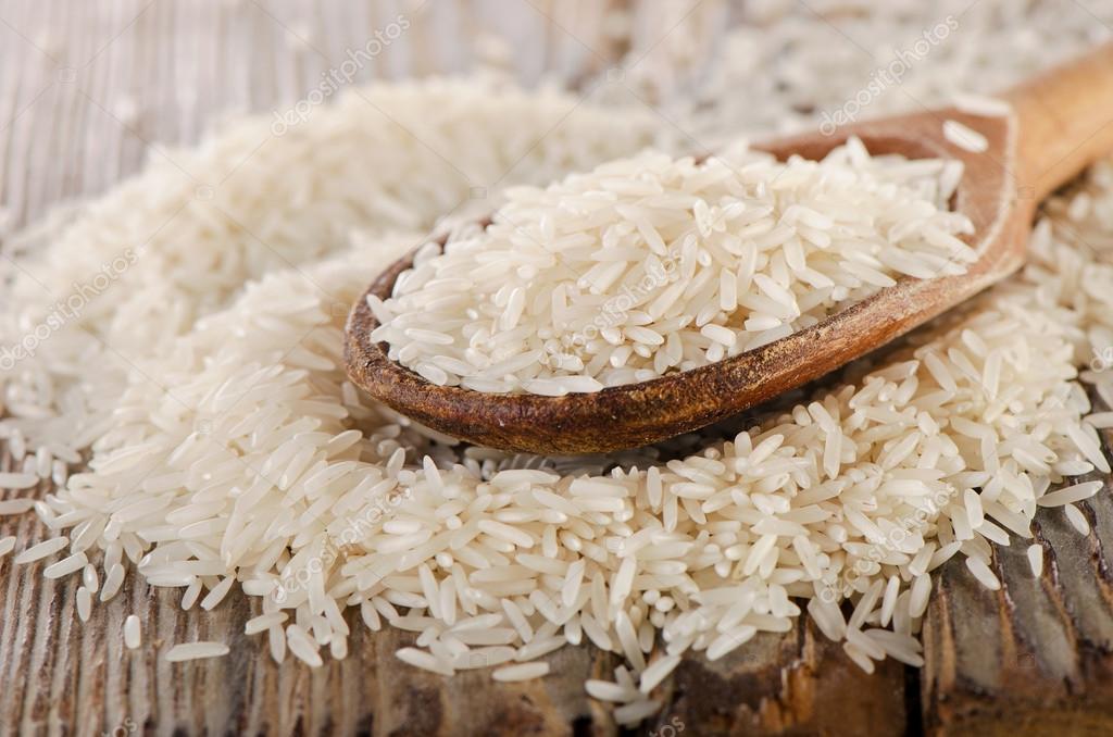 Uncooked rice in a wooden spoon — Stock Photo © bit245 #65184551