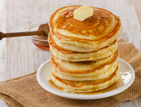 Stack of Small pancakes with maple syrup on wooden table. - Stock Image ...