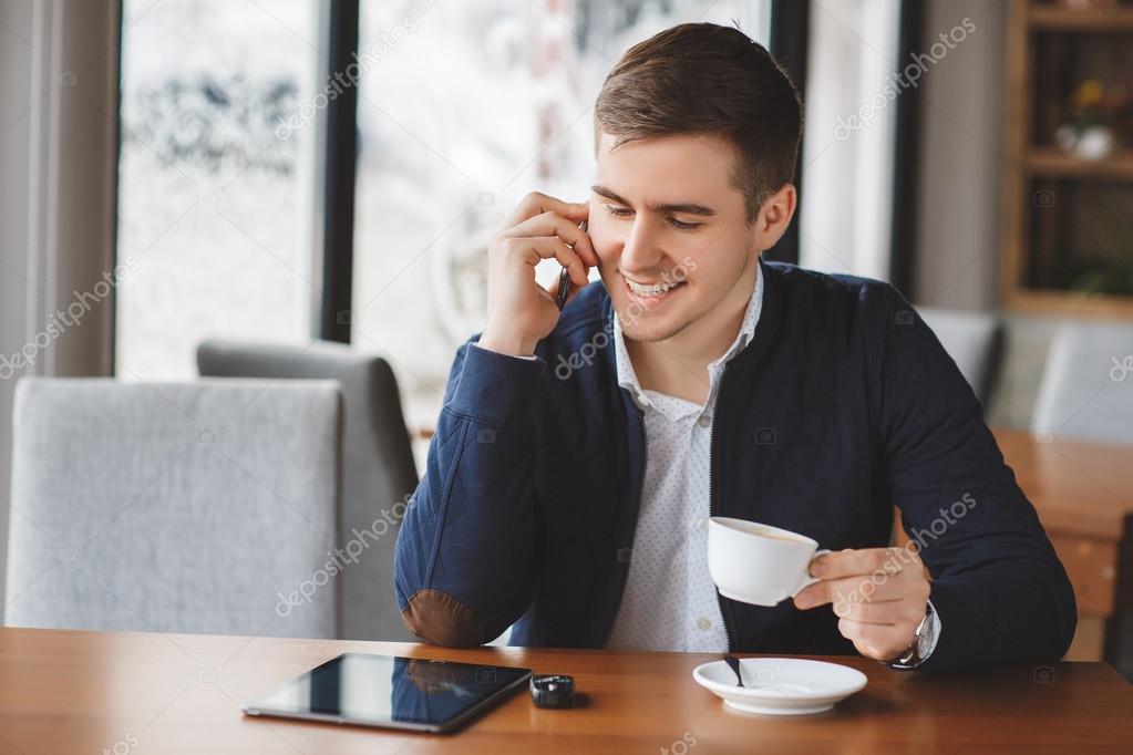 Hombre guapo tomando caf y usando smartphone en la cafeter a 2024