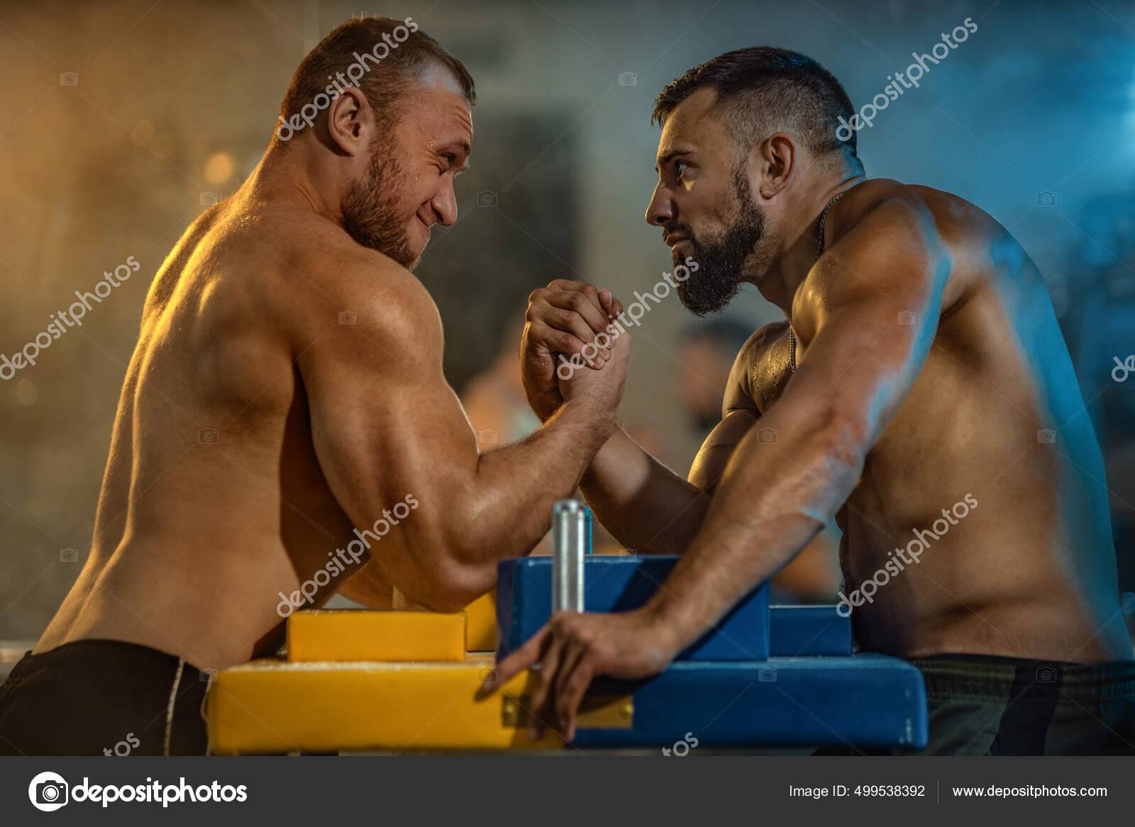 Two strong athletes in the gym compete in arm wrestling. Bodybuilders ...