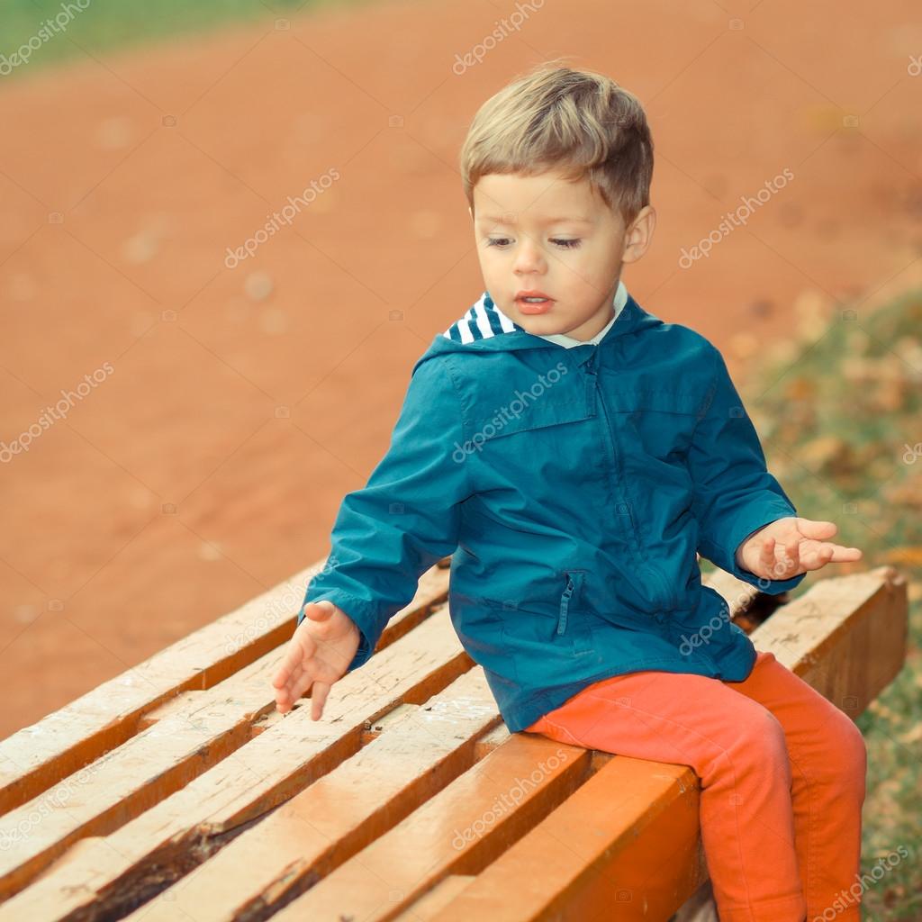 Little boy sitting on bench in the park Stock Photo by ©RumisPhoto ...