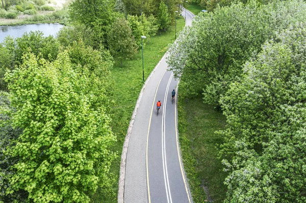 two cyclists ride bikes on bicycle path in city park at spring day ...
