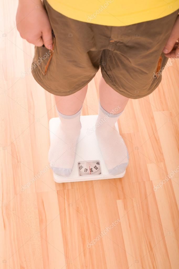 Boy measures weight on floor scales Stock Photo by ©Nick_Thompson 65695385