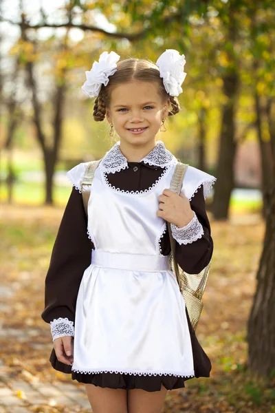 Portrait of a beautiful young first-grader in a festive school u ...