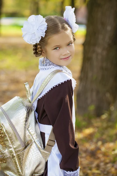 Portrait of a beautiful young first-grader in a festive school u ...