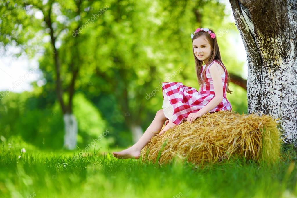 Little girl sitting on a haystack — Stock Photo © MNStudio #112882696