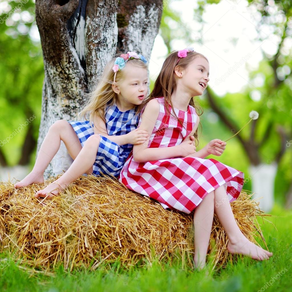 Little sisters sitting on haystack — Stock Photo © MNStudio #119492972