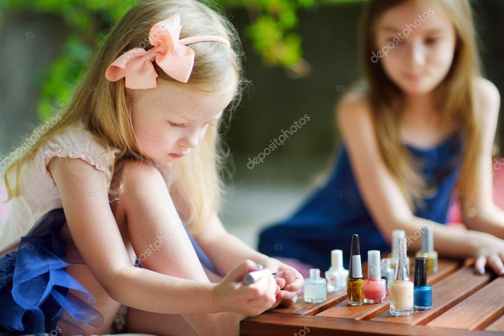 Adorable little girls painting nails Stock Photo by ©MNStudio 119493636