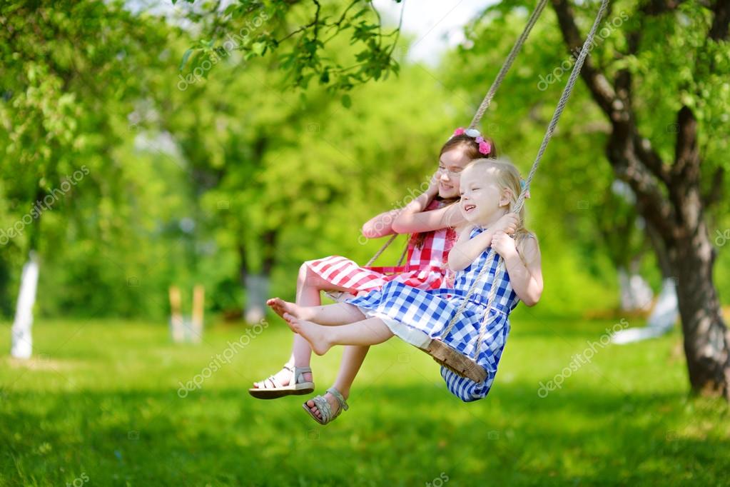 Little sisters having fun on a swing Stock Photo by ©MNStudio 123166198