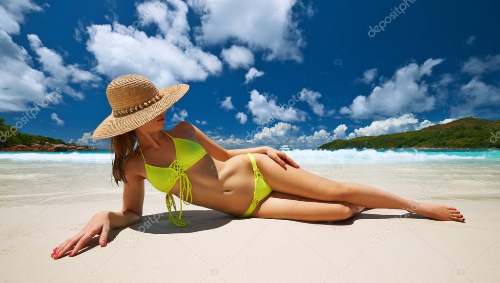 Mujer en bikini amarillo acostada en la playa 2025