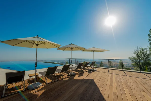 Deck chairs and infinity pool over tropical lagoon Stock Photo by ...
