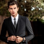 Elegant handsome man in classical grey suit poses near wooden fence ...