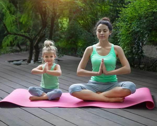 Mother and daughter doing exercise practicing yoga outdoors - Stock ...
