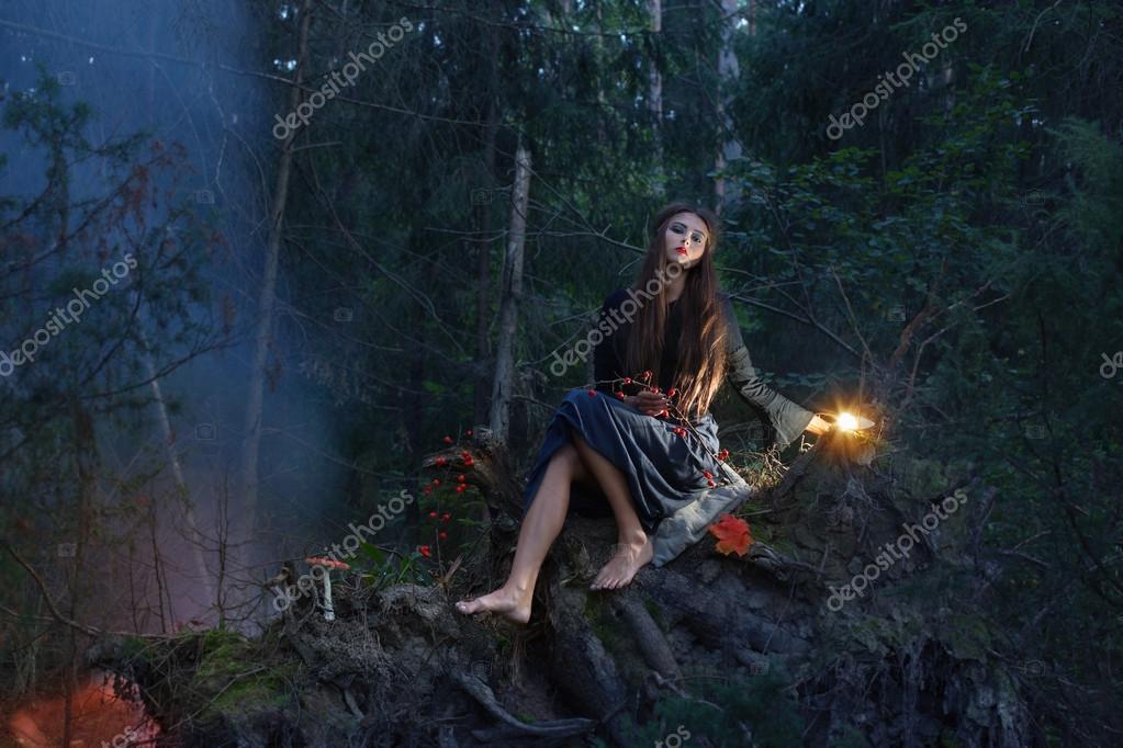 Beautiful witch sitting on a tree trunk in the forest Stock Photo by ...