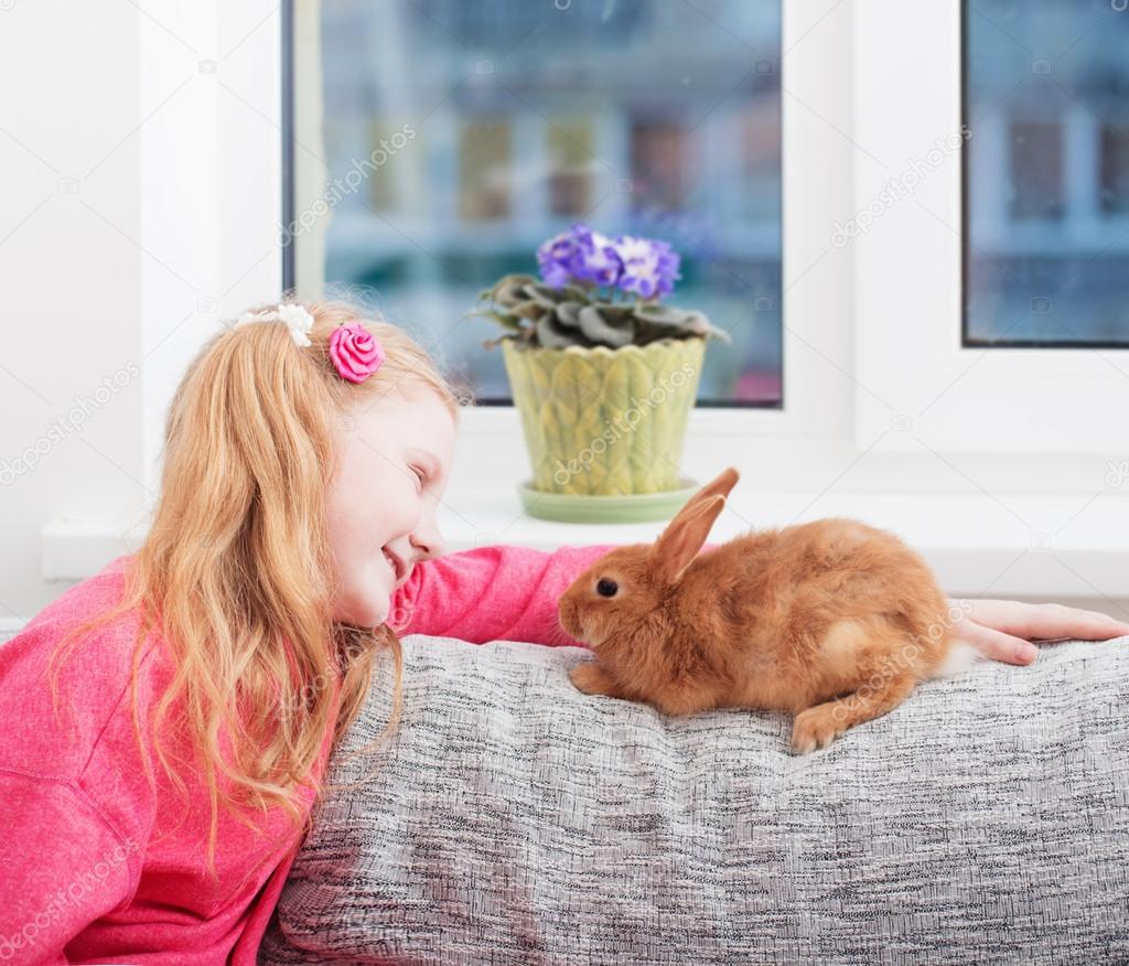 Smiling girl with rabbit indoor Stock Photo by ©Kruchenkova 72107049