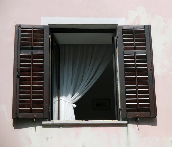 Old window with open shutters with flowers on the window sill on the ...