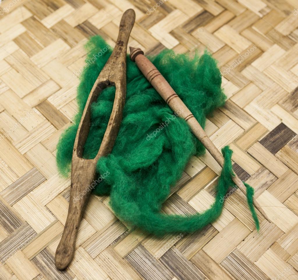 Green wool and old spindle close-up on wooden background. Tools for ...