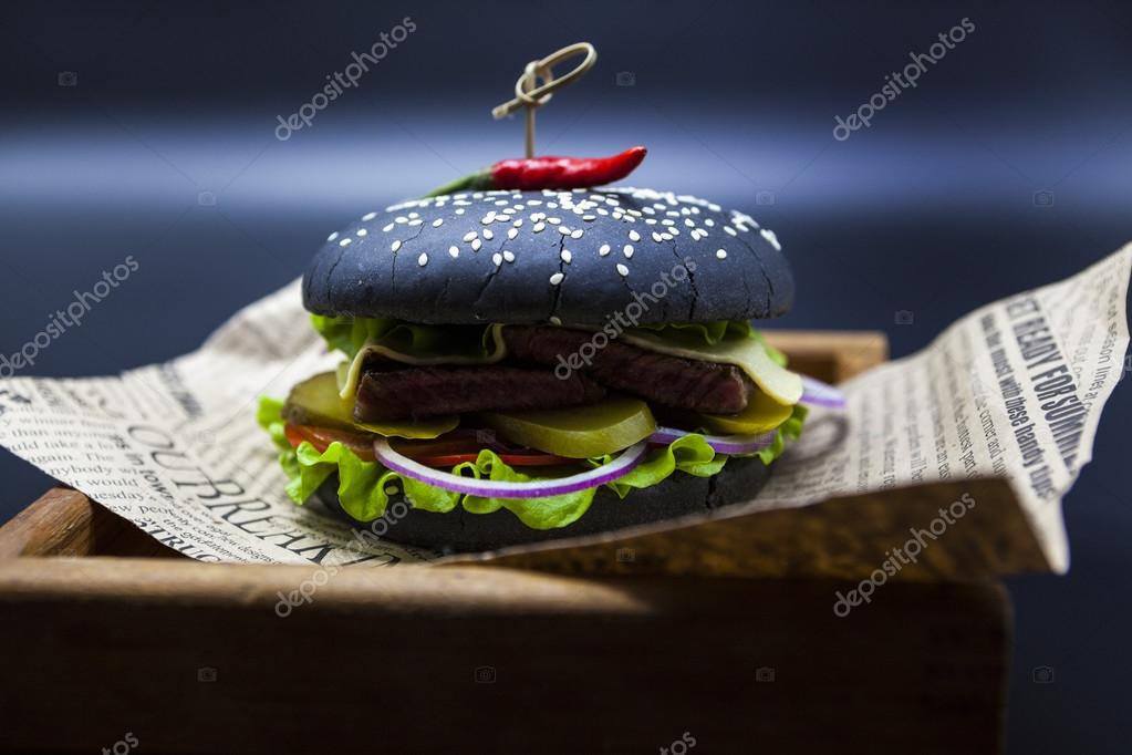 Black burger. A burger with a black roll slices of juicy marble beef ...
