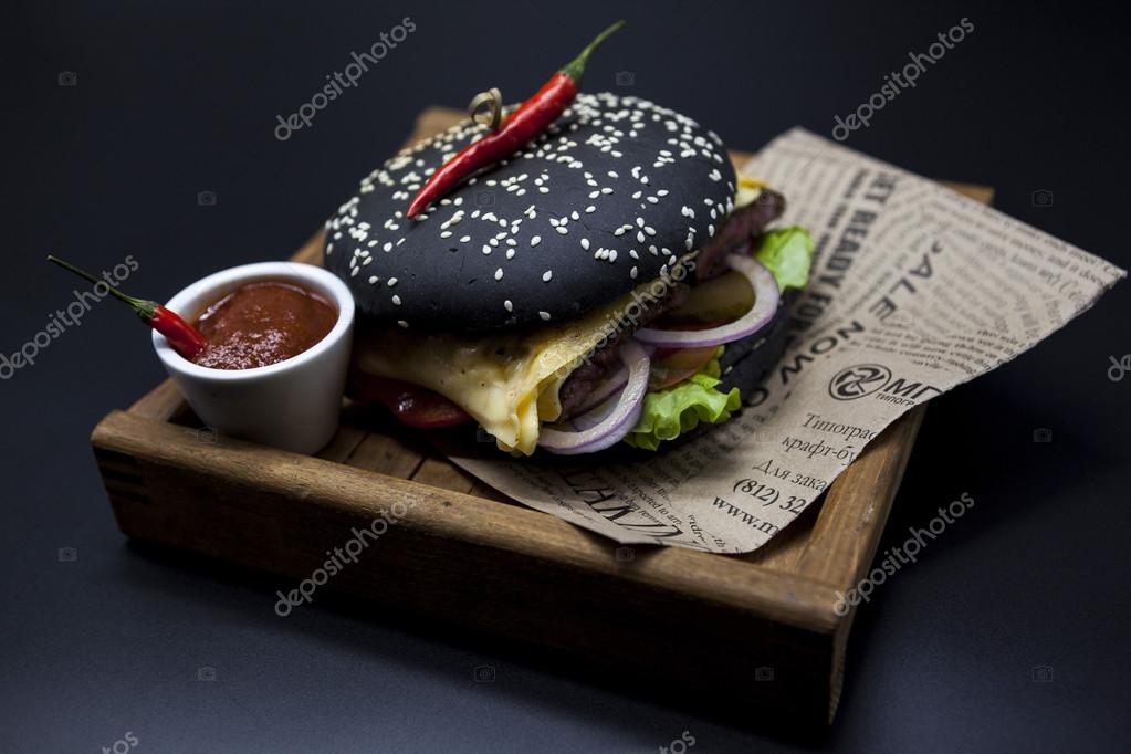 Black burger. A burger with a black roll slices of juicy marble beef ...
