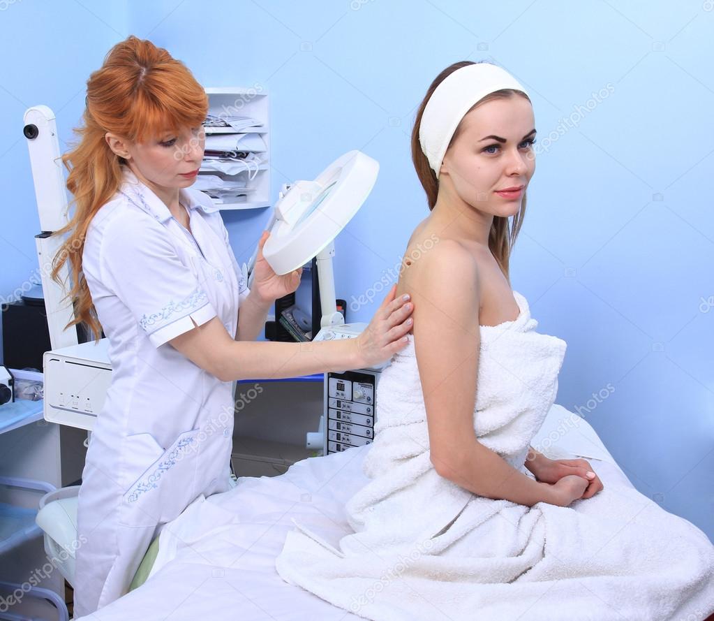 Doctor inspecting woman patient skin Stock Photo by ©nikolasvn 68758571