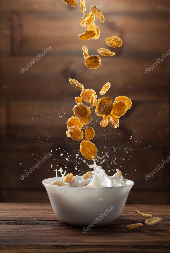Falling corn flakes with milk splash on wood — Stock Photo © artjazz ...