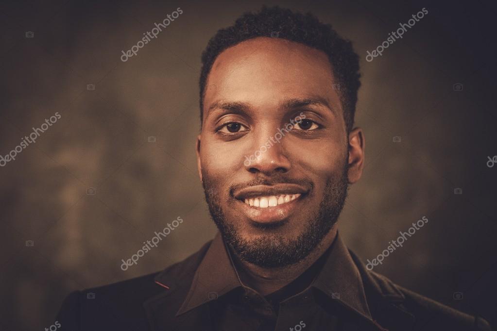 Smiling young black man posing on dark background. Stock Photo by ...
