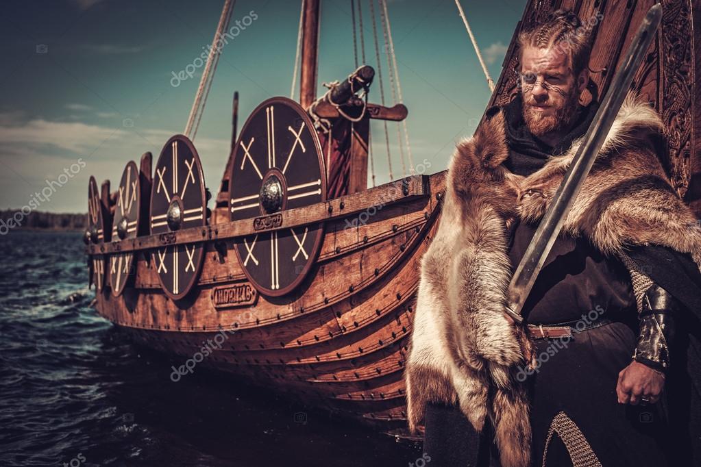 Viking warrior with sword and shield standing near Drakkar on the ...