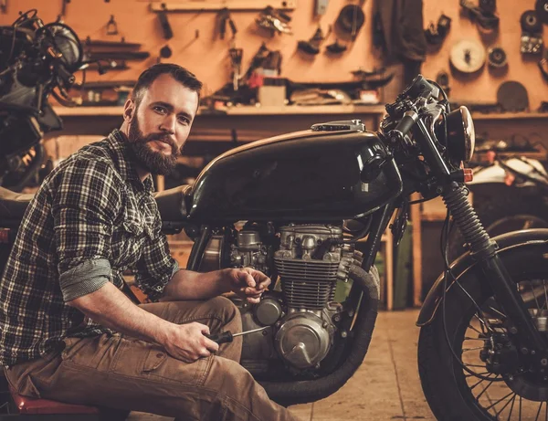 Mechanic building vintage style cafe-racer motorcycle in custom garage ...