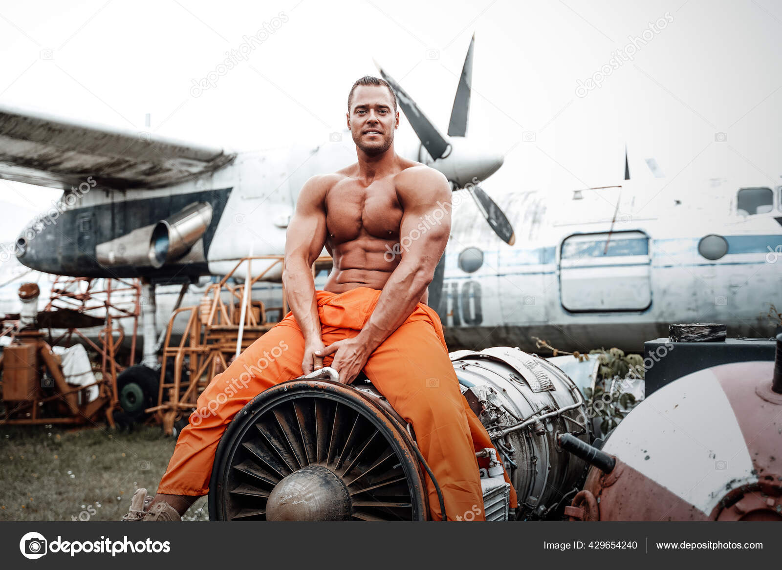 Positive bodybuilder sitting on a engine of airplane in daytime Stock ...