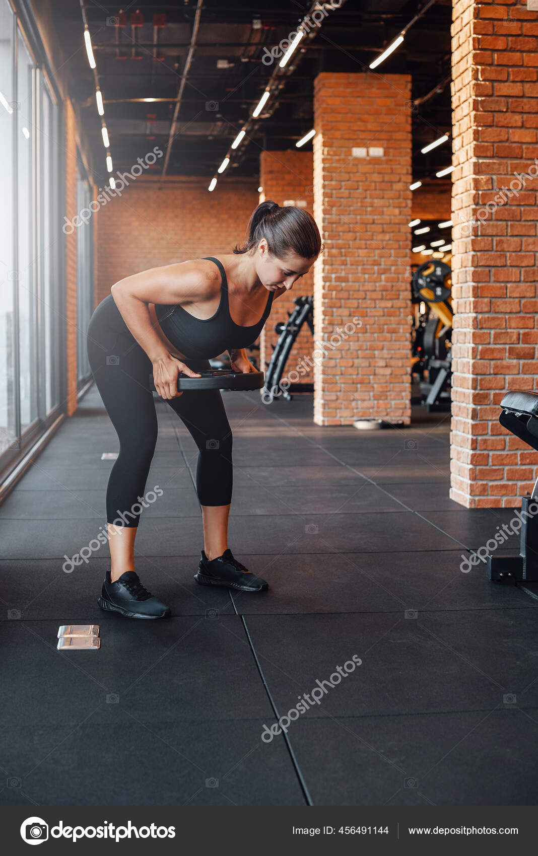 Female bodybuilder trains lifting a dumbell in modern gym Stock Photo ...