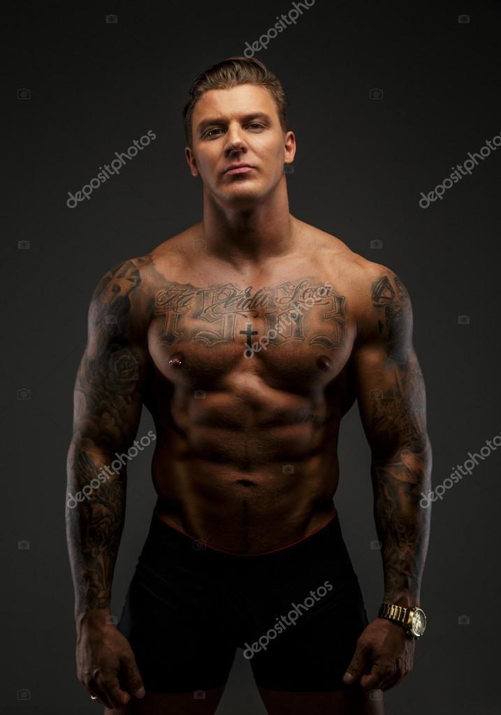 Muscular man with tattooes in deep shadows — Stock Photo © fxquadro ...