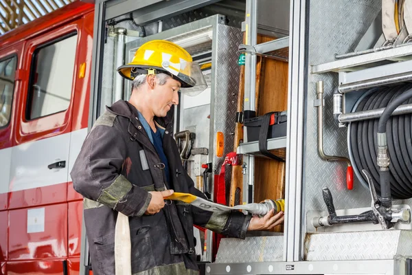 Firefighter Fixing Water Hose In Truck At Fire Station - Stock Image ...