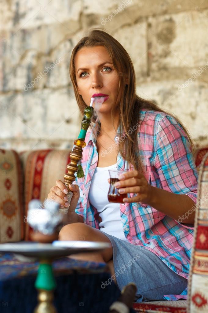 Woman smoking a hookah and drinking tea in a cafe, Istanbul, Tur ...
