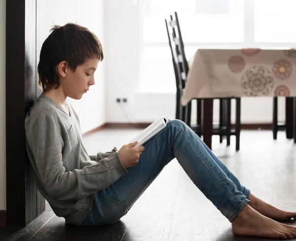 Young boy sitting at desk read the book and whright down in notebook ...