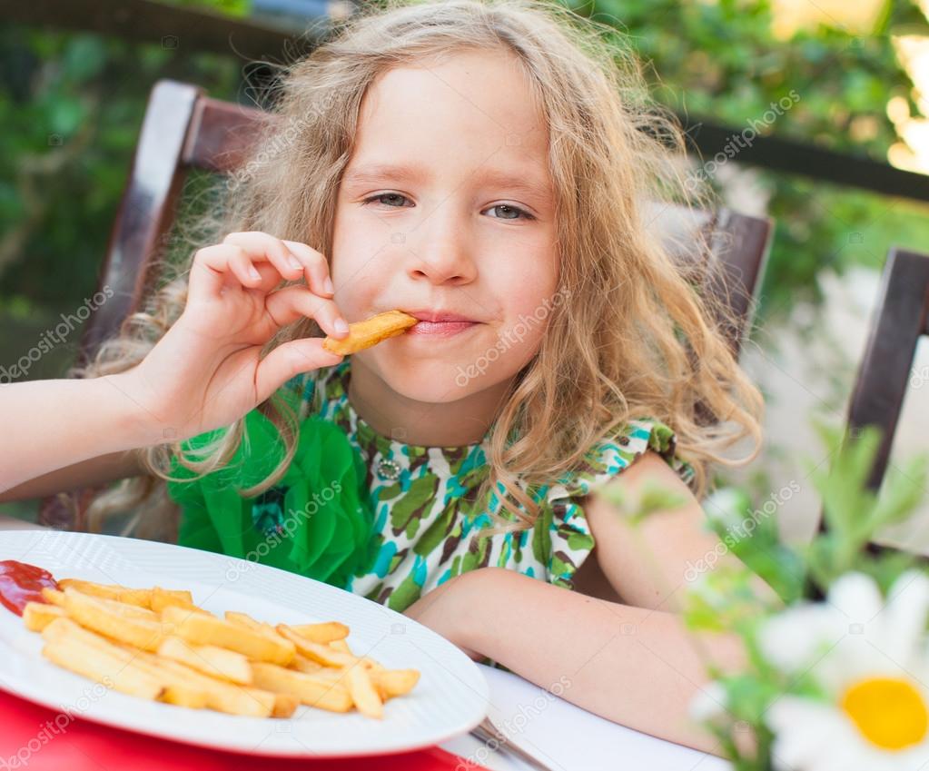 Child eating potato chips in the cafe Stock Photo by ©TatyanaGl 99300688