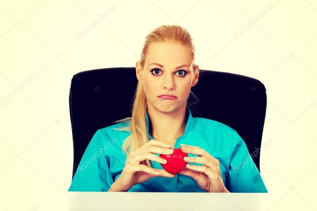 Doctora o enfermera preocupada sentada detrás del escritorio y ... Doctora o enfermera preocupada sentada detrás del escritorio y ...