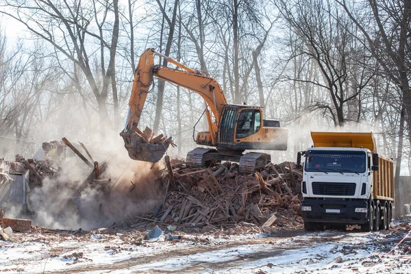 yellow excavator loading a dump truck with debris and trash after ...