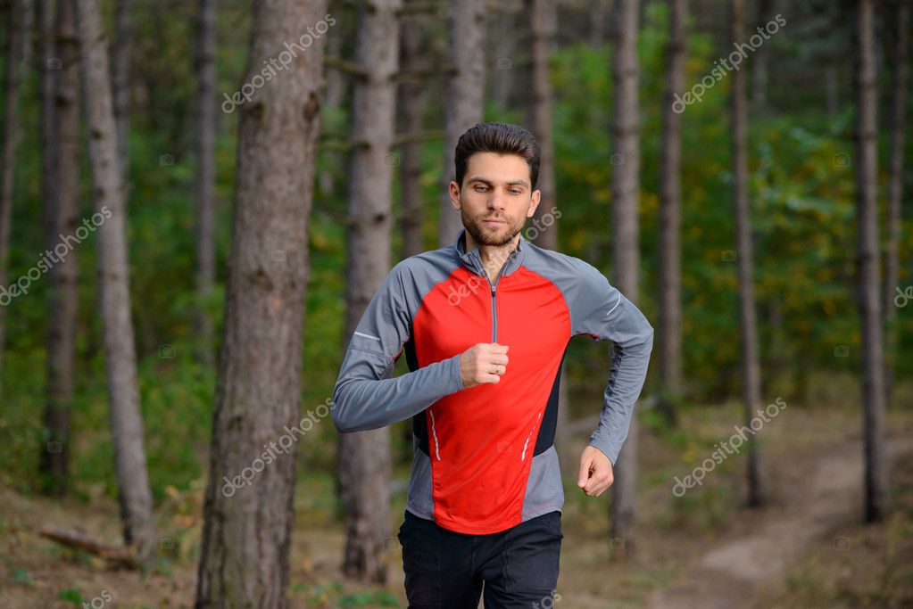 Young Man Running on the Trail in the Wild Pine Forest. Active ...
