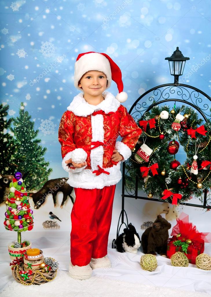 Beautiful little boy in a red suit and cap Christmas decorations ...