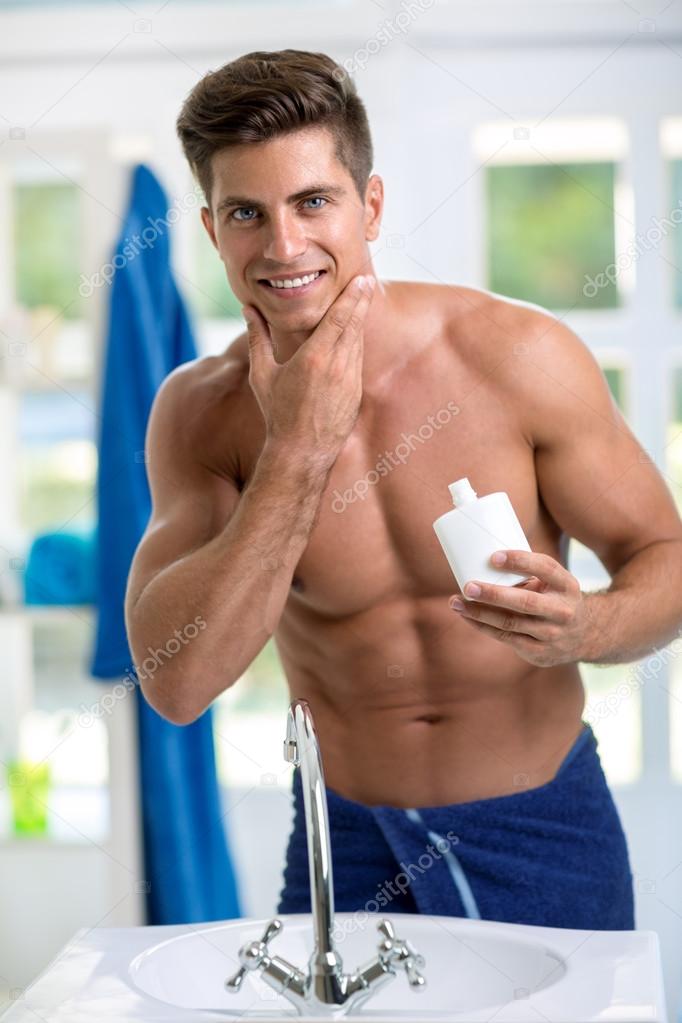 Smiling handsome man applying after shave — Stock Photo © luckybusiness #86579646