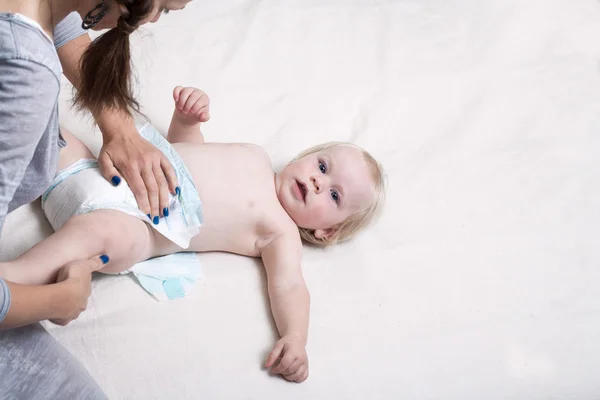 Mother changes diapers — Stock Photo © AChubykin #81517648