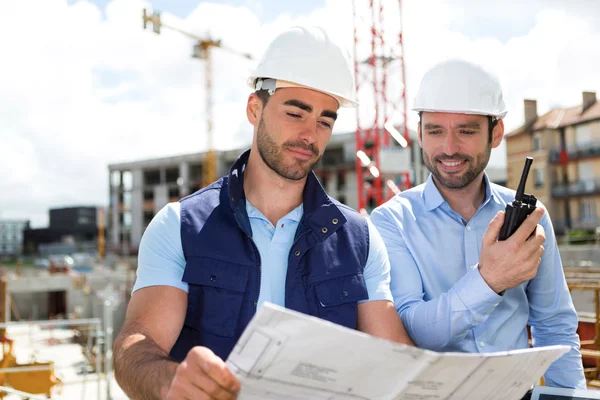 Engineer and worker watching blueprint on construction site Stock Photo ...